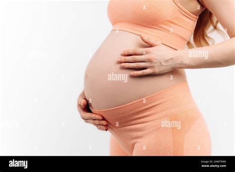 Close-up of a pregnant woman touching her belly on a white background ...