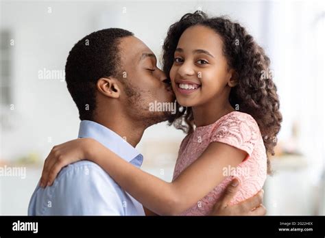 Handsome black father kissing his cute little daughter Stock Photo - Alamy