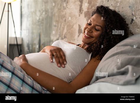 Beautiful smiling pregnant woman touching her belly Stock Photo - Alamy