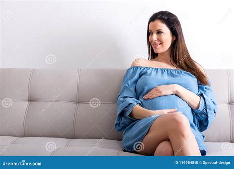 A Pregnant Woman Sitting on a Sofa with Hands on Her Belly Stock Photo - Image of elegant ...