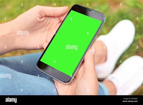 Woman holding smartphone with green screen outdoors, closeup. Gadget display with chroma key ...