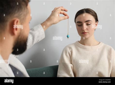 Psychologist using pendulum while working with patient during hypnosis session indoors Stock ...