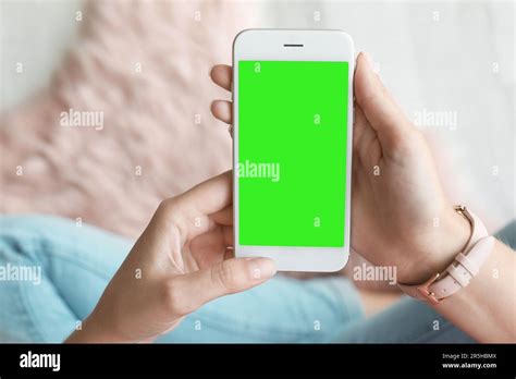 Chroma key compositing. Woman holding smartphone with green screen indoors, closeup. Mockup for ...