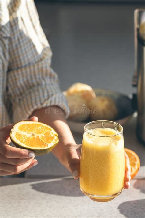 A Glass of Freshly Squeezed Orange Juice and Half an Orange in Female Hands. Stock Image - Image ...
