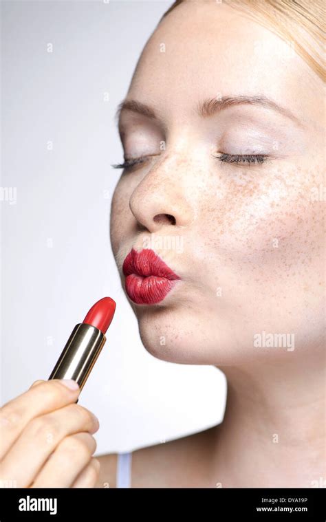 Young woman putting on lipstick Stock Photo - Alamy