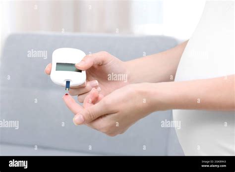 Pregnant woman testing glucose level with digital glucometer indoors ...
