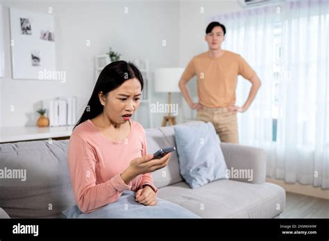 Shocked jealous Asian girlfriend suspecting infidelity by reading text messages on her cheating ...