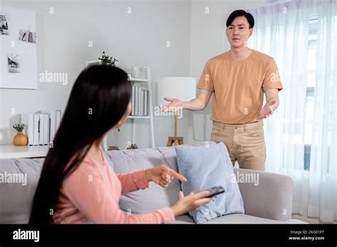 Shocked jealous Asian girlfriend suspecting infidelity by reading text messages on her cheating ...