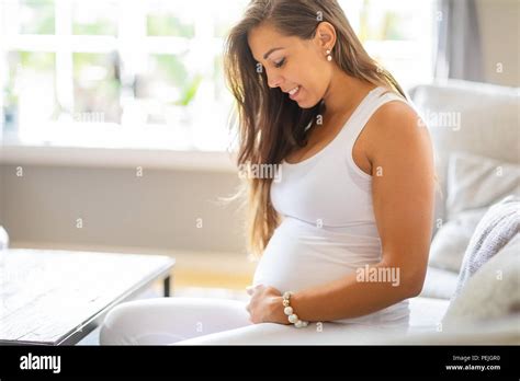 Smiling pregnant woman lying on the sofa touching her belly Stock Photo - Alamy