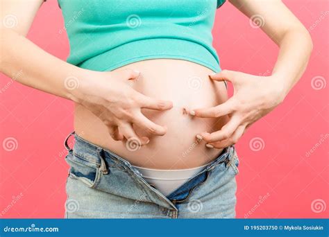 Close Up of Pregnant Woman Dressed in Opened Jeans Scratching Her Belly at Colorful Background ...