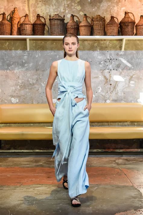 a model walks down the runway in a light blue jumpsuit with cutouts on ...
